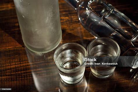 병 근처에 알코올냉동 안경 어두운 갈색 테이블에 음료 검은 색 배경에 투명 한 기구 유리 아래 오래 된 초라한 보드입니다 0명에