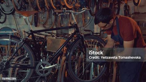 테마 중소 기업 자전거 수리 보호 안경 장갑과 Fartuhe에 젊은 갈색 머리 백인 남자는 수리 및 차고 작업장에서 림