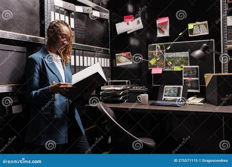 Woman Police Investigator Reading Case File In Office Room Stock Image
