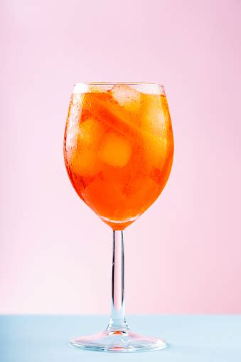Aperol Spritz 칵테일은 분홍색 파란색 배경에 유리로 되어 있습니다 오렌지와 얼음 조각을 곁들인 칵테일 Aperol