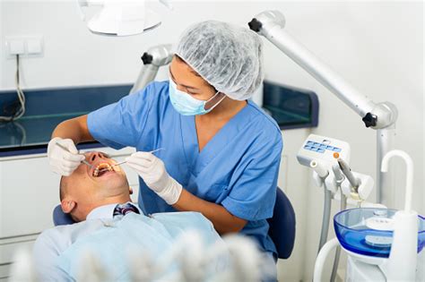 보호 마스크에 자격을 갖춘 여성 치과 의사가 남자 환자를 치료합니다 30 34세에 대한 스톡 사진 및 기타 이미지 30 34