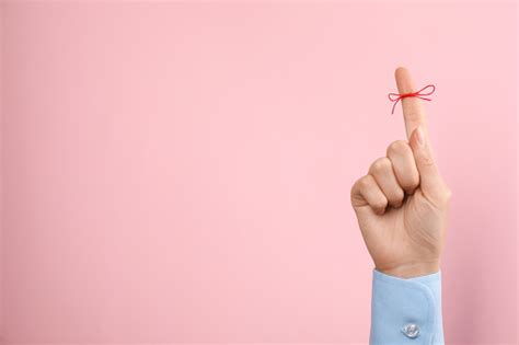 분홍색 배경 클로즈업 텍스트 공간에 대한 알림으로 묶인 빨간 활로 검지 손가락을 보여주는 여성 가리키기에 대한 스톡 사진 및