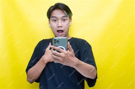 Premium Photo A Cheerful Asian Man With Peek A Boo Hair Uses Airpods