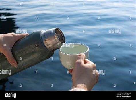 Womans Hand Pouring Hot Drink From Thermos Into Glass While Pouring A