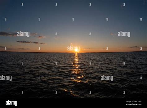 A Stunning Sunset Casts A Golden Glow Upon The Tranquil Surface Of A Shimmering Body Of Water