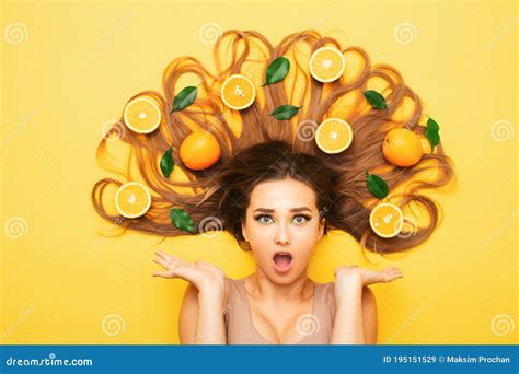 Shocked Girl Lying On Studio Background With Orange Fruits On Long Hair