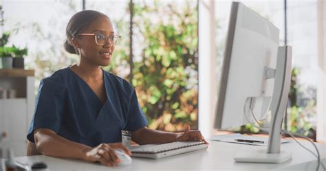 일상적인 병원 운영을 위해 데스크톱 컴퓨터를 사용하는 아프리카 의료 간호사 공공 의료 시설의 현대 사무실에서 온라인 의료 작업을 위해 Pc를 사용하는 아름다운 젊은 클리닉