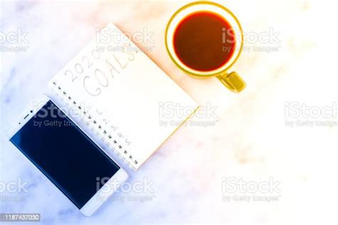 2020 새해 목표 계획 흰색 대리석 배경에 메모장에 행동 텍스트 텍스트에 대한 복사 공간이있는 빈 노트 용지에 2020 목표 대리석 배경 위에 커피와 스마트폰 한 잔 0