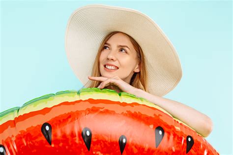 수영복을 입은 여름 모자를 쓴 아름다운 소녀가 고립된 파란색 배경에 풍선 반지를 끼고 서 있습니다 공기 주입에 대한 스톡 사진
