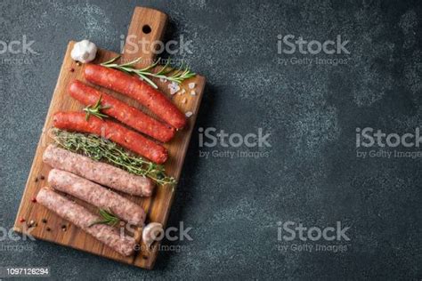 백 리 향 로즈마리 올리브 기름 및 마늘 어두운 콘크리트 테이블에 나무도 마 보드에 모듬된 신선한 소시지 검은 바탕에 저녁