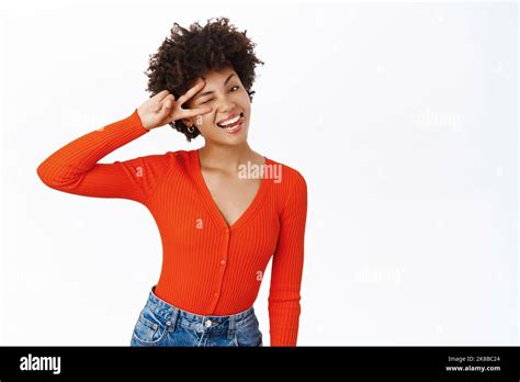 Positive Girl Shows Peace V Sign Gesture Near Eyes And Smiles Broadly