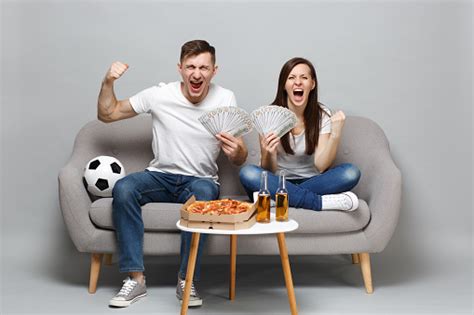 비명 부부 여자 남자 축구 팬 응원 마음에 드는 팀 홀드 팬 달러 지폐 현금 돈에 돈에 고립 된 위 인 제스처 회색 배경 스포츠