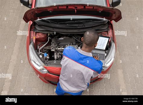 Young Male Mechanic Using Laptop While Examining Car Engine Stock Photo ...