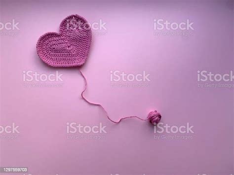분홍색 배경에 분홍색 색상의 니트 하트 위의 사진 제품을 만드는 개념입니다 Crocheting 발렌타인 데이의 개념 겨울에 대한