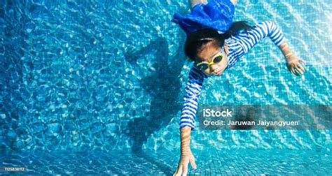 어린 소녀는 끝내 수영 수영장의 보드를 터치 합니다 여자 수영 및 수영복과 파란 수영장에 다이빙 어린이 수영 또는 건강 한 라이프 스타일 개념을 배운다 아이에 대한 스톡