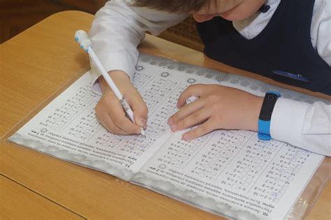 Premium Photo A Girl Solves Tasks In A Math Notebook In A Classroom