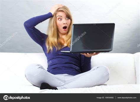 Scared Woman Sitting On Sofa And Looking At Laptop Modern Technology