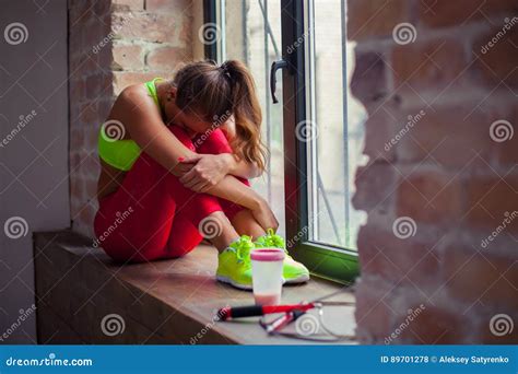 Young Beautiful Girl Is Sitting On The Windowsill And Resting Stock