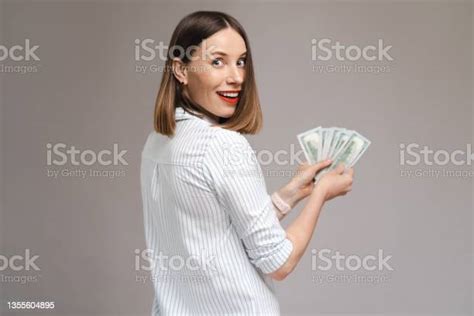 어깨 너머로 보이는 회색 배경에 달러를 들고 있는 감동한 여성 긍정적인 감정 표현에 대한 스톡 사진 및 기타 이미지 긍정적인