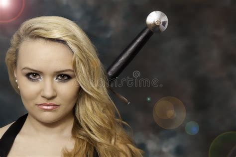 Young Beautiful Blonde Woman Or Girl With A Sword Behind The Back Stock