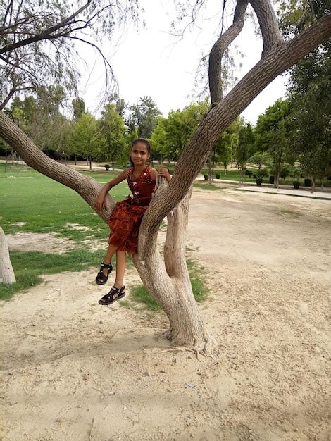 Premium Photo Full Length Of Girl Sitting On Tree Trunk At Park