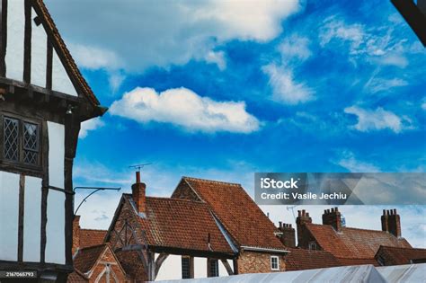 영국 노스 요크셔 주 요크에 위치한 푹신한 구름과 함께 생생한 푸른 하늘 아래 전통적인 반 목조 주택과 테라코타 지붕이있는 기이 한 유럽 마을 0명에 대한 스톡 사진 및