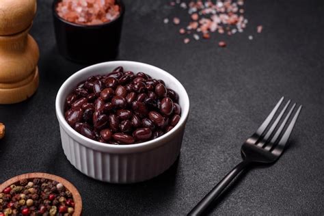 어두운 콘크리트 배경에 흰색 접시에 검은 통조림 콩 프리미엄 사진
