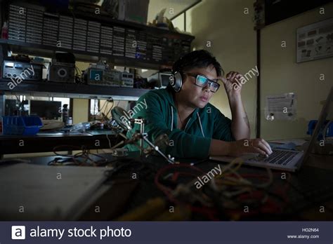 Female Computer Programmer Working At Laptop Wearing Headphones In Dark