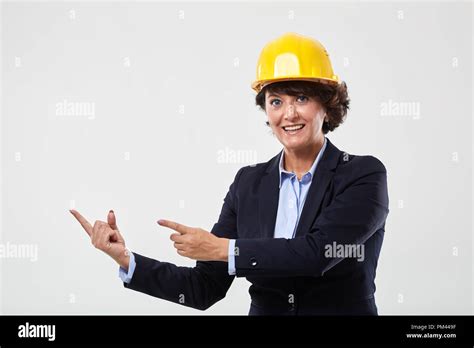 Mature Engineer Woman In Hard Hat Indicating Towards The Copyspace
