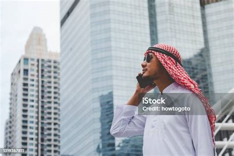 스마트 폰 응용 프로그램을 사용하는 이슬람 남자는 스마트 폰 무슬림 현대 아랍 도시를 들고 손에 일정 의제를 구성합니다 아랍 남성 착용 히잡과 무슬림 정장 드레스 보내는