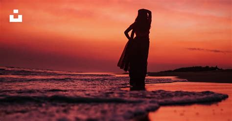 Foto Silueta De Mujer De Pie En La Playa Durante La Puesta Del Sol