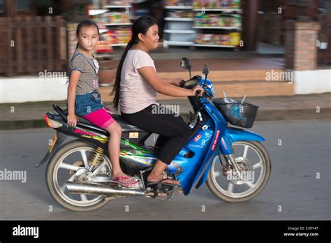 A Girl Rides Pillion On Her Mothers Motorbike In Luang Prabang Laos