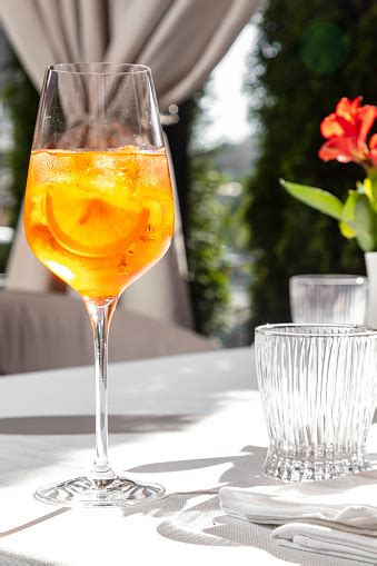 Aperol Spritz 칵테일 흰색 식탁보가 있는 테이블에는 Aperol Spritz 칵테일이 있는 높은 긴 다리에 유리가