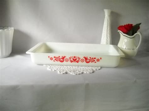 A White Tray With Red Designs On It Next To Vases And A Lace Doily