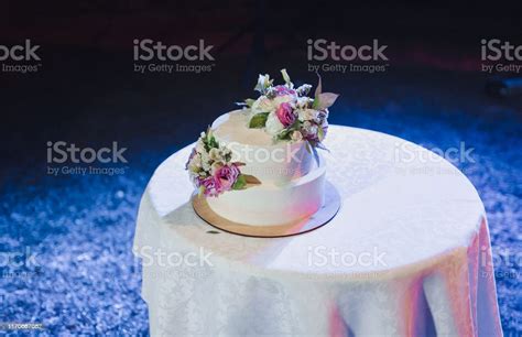 장미로 장식된 아름다운 웨딩 케이크가 레스토랑의 원형 테이블에 서 있습니다 웨딩 파티 맛있는 파이 0명에 대한 스톡 사진 및