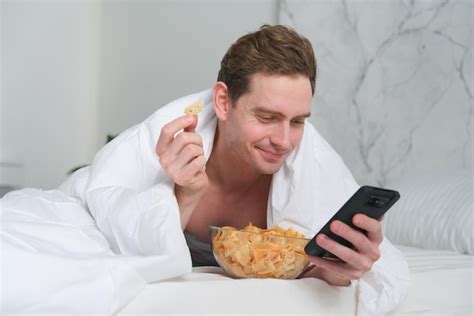 Premium Photo Young Man Eating Chips In Bed Bedroom Fast Junk Food