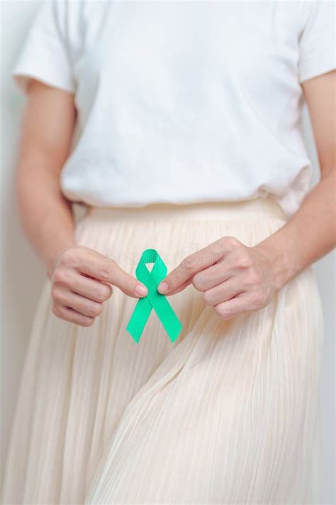 Woman Holding Teal Ribbon On Abdomen For January Cervical Cancer