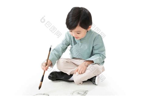 小男孩盘腿坐着拿毛笔写字图片 包图网企业站