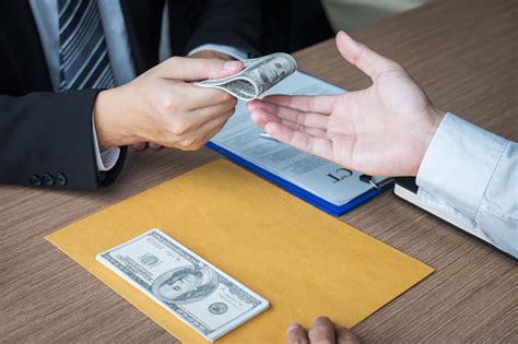 불법 적인 돈에 부정직 한 부정 행위 뇌물 돈을 주는 사업가 달러 지폐의 형태로 제공 하는 동안 성공 계약 계약 뇌물 및 부패 개념에 거래를 제공 계약서에 대한 스톡 사진