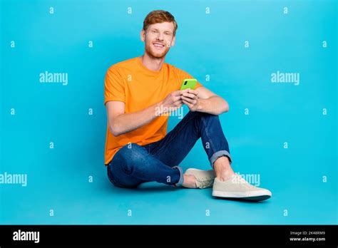Full Length Photo Of Funky Positive Man Wear Orange T Shirt Sitting