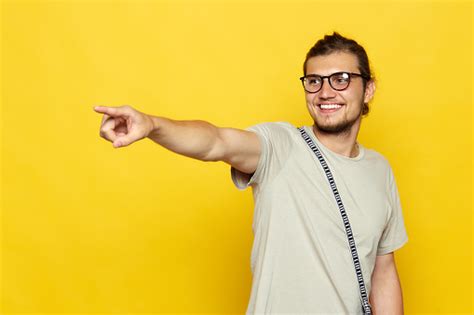 노란색 벽에 복사 공간에 T 셔츠 포인트를 입고 세련 된 면도 남자는 즐거운 무언가를 보여줍니다 웃는 모습 가리키기에 대한 스톡 사진 및 기타 이미지 Istock