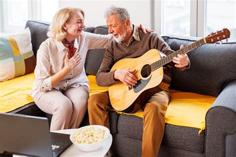 집에서 쾌활한 선배가 어쿠스틱 기타를 연주하면서 아내와 시간을 즐기고 있다 2명에 대한 스톡 사진 및 기타 이미지 2명 60 69세 65 69세 Istock