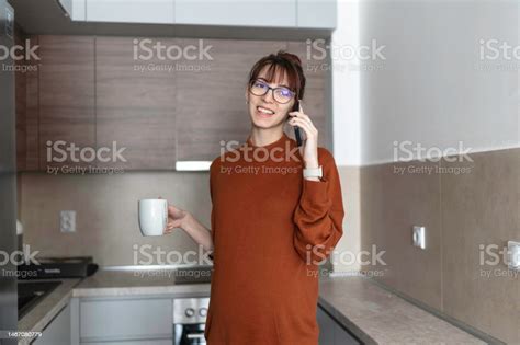 부엌에서 커피 한 잔을 들고 있는 쾌활한 임산부 아름다운 여자는 뜨거운 음료를 즐긴다 가정 생활에 대한 스톡 사진 및 기타