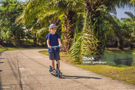 공원에서 킥 스쿠터에 아이 아이들은 롤러 보드를 스케이트하는 법을 배웁니다 화창한 여름 날에 어린 소년 스케이트 안전한 주거 거리에서 어린이를위한 야외 활동 유치원 아이를