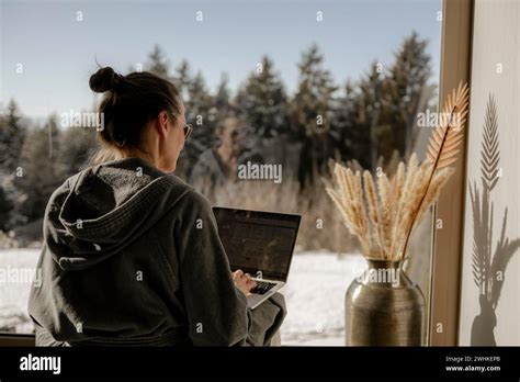 Woman In Bathrobe Sitting With A Laptop On Her Lap In A Garden Stock