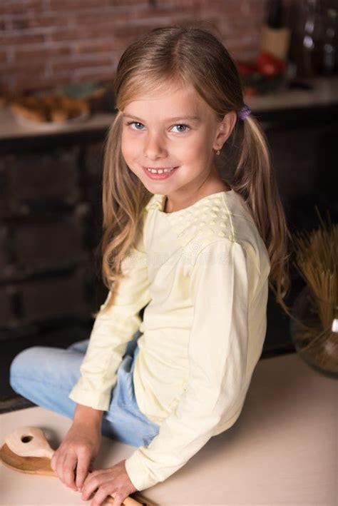 Smiling Girl Holding Wooden Spoons And Sitting On The Table Stock Image