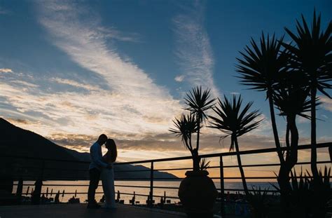Um casal se beijando na frente de palmeiras ao pôr do sol Foto Premium