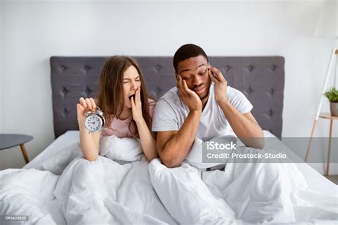인종 간 결혼 한 부부는 아침에 깨어있는 데 문제가 알람 시계와 침대에 졸린 앉아 2명에 대한 스톡 사진 및 기타 이미지 2