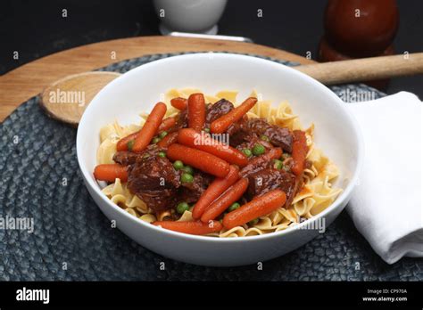 Beef Stew With Vegetables Over Egg Noodles In White China Bowl With