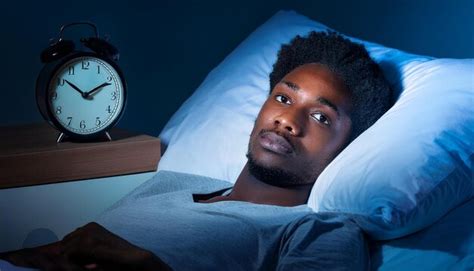 A Young Man Lying In Bed With His Eyes Wide Open Staring At The Ceiling